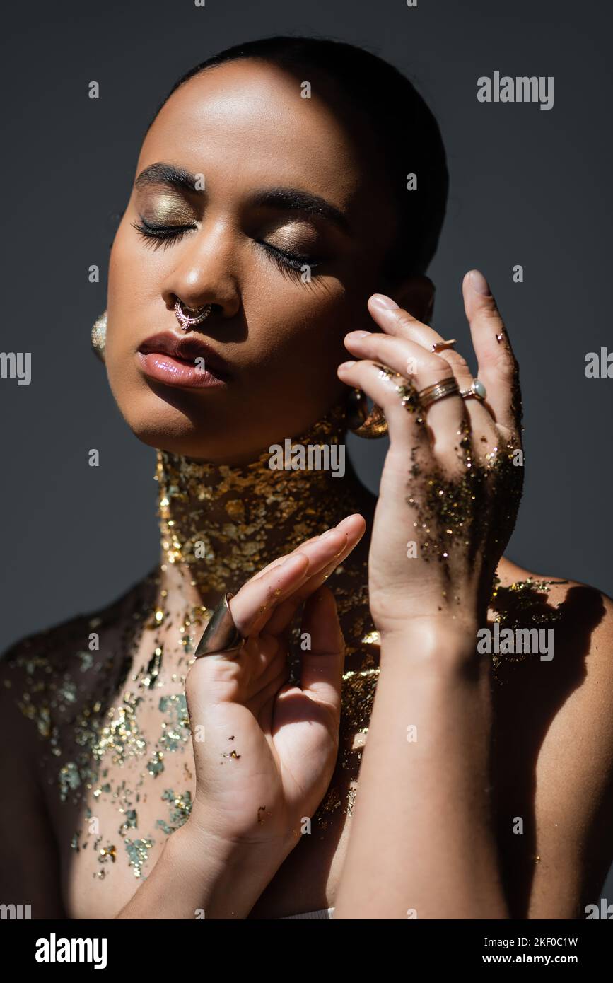 Fashionable african american woman with piercing and golden foil on ...