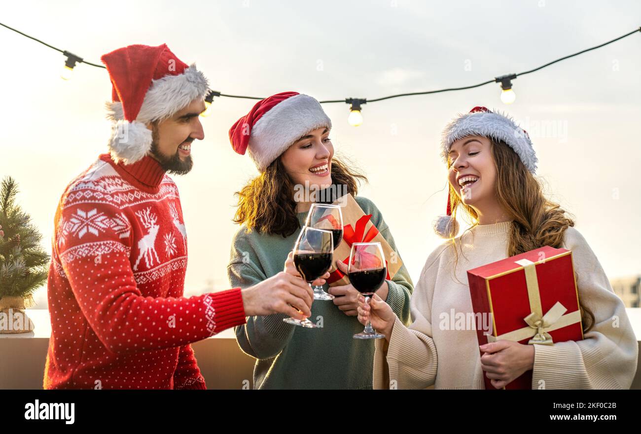 Happy friends are celebrating Christmas outdoors. Adults are having fun ...