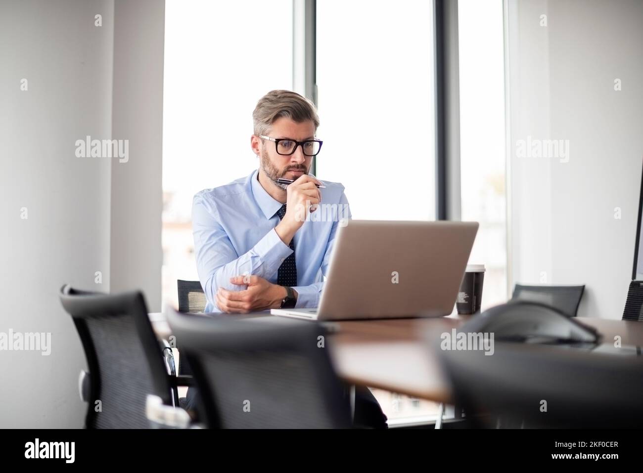 Care-worn middle aged businessman working at the office and using ...