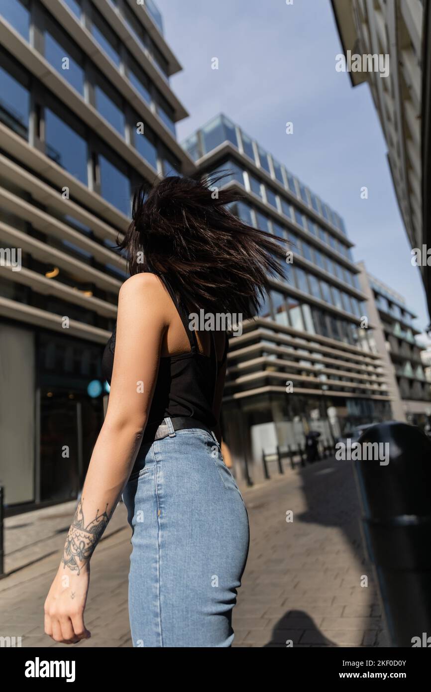 Back view of tattooed woman standing on blurred urban street in Prague ...
