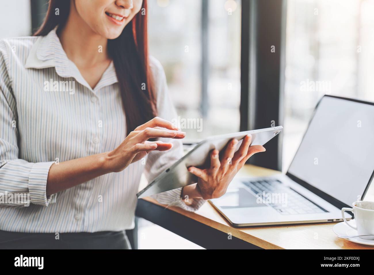 Portrait of an Asian female employee using a tablet computer at work ...