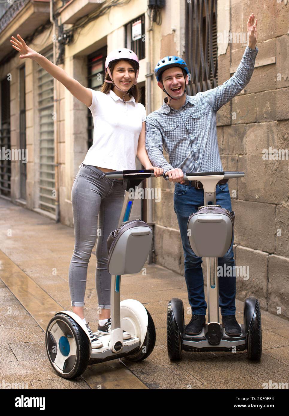young couple guy and girl walking on segway in streets of european city ...
