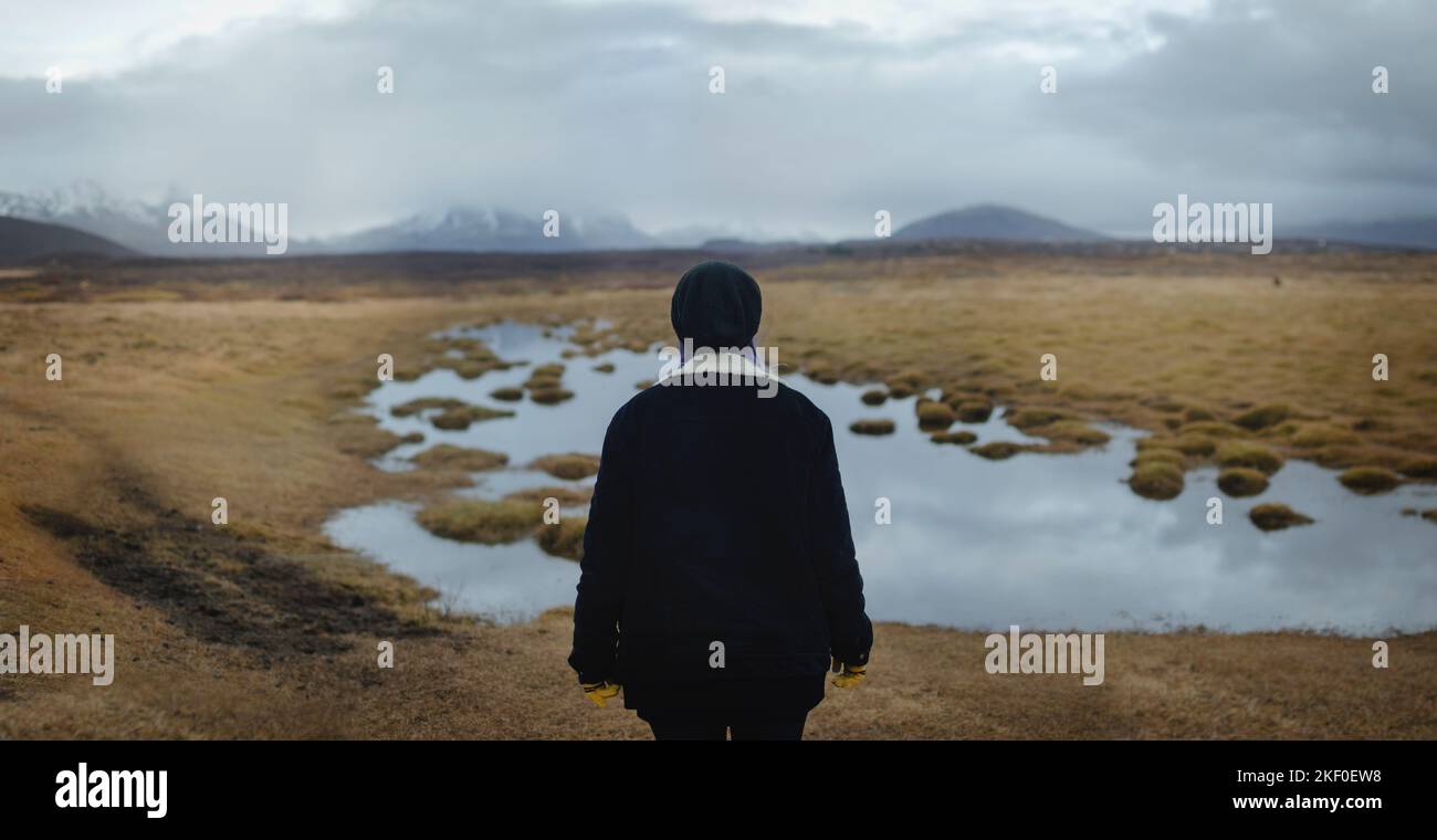 Person standing in front of an open landscape in Iceland with mountains ...