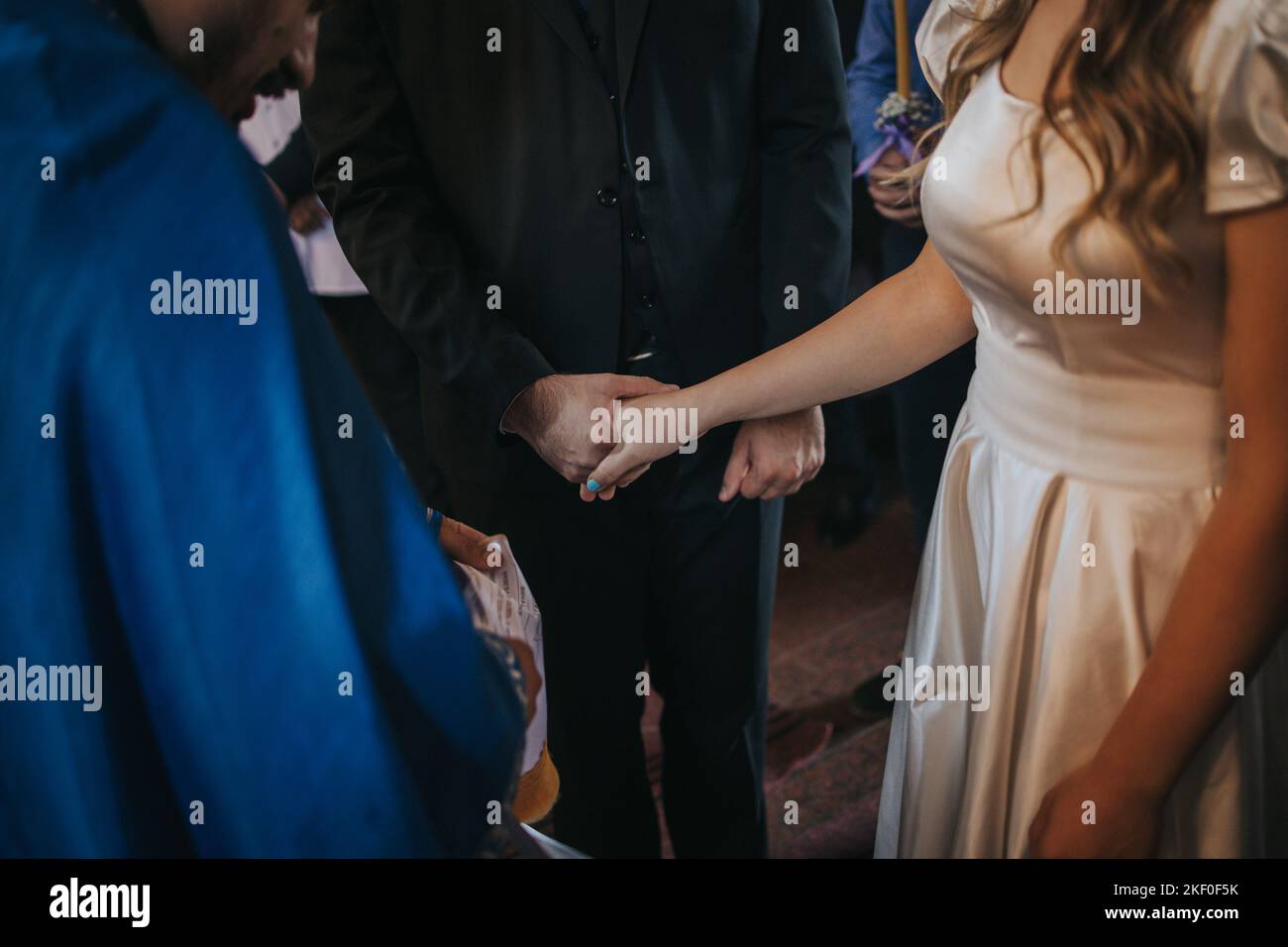A closeup of groom and bride standing in front of priest Stock Photo ...