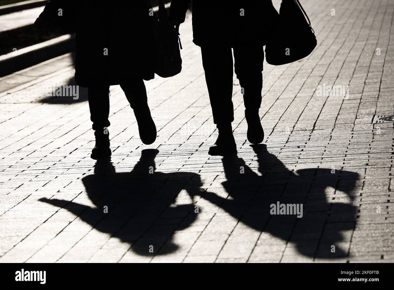 Silhouettes and shadows of two women walking down on the city street ...