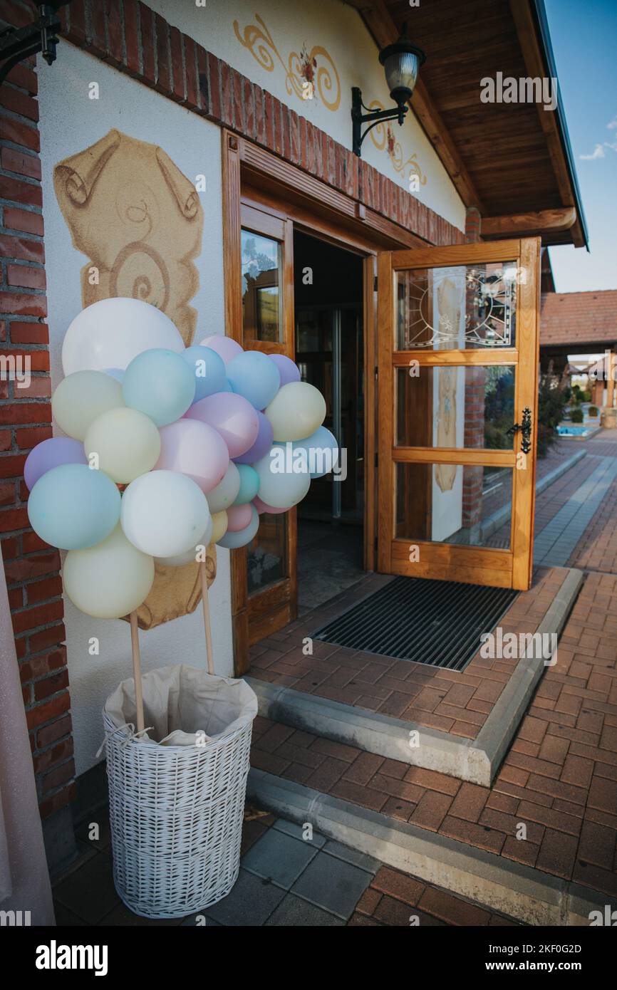 A vertical shot of a bunch of balloons on a bucket in front of a house ...