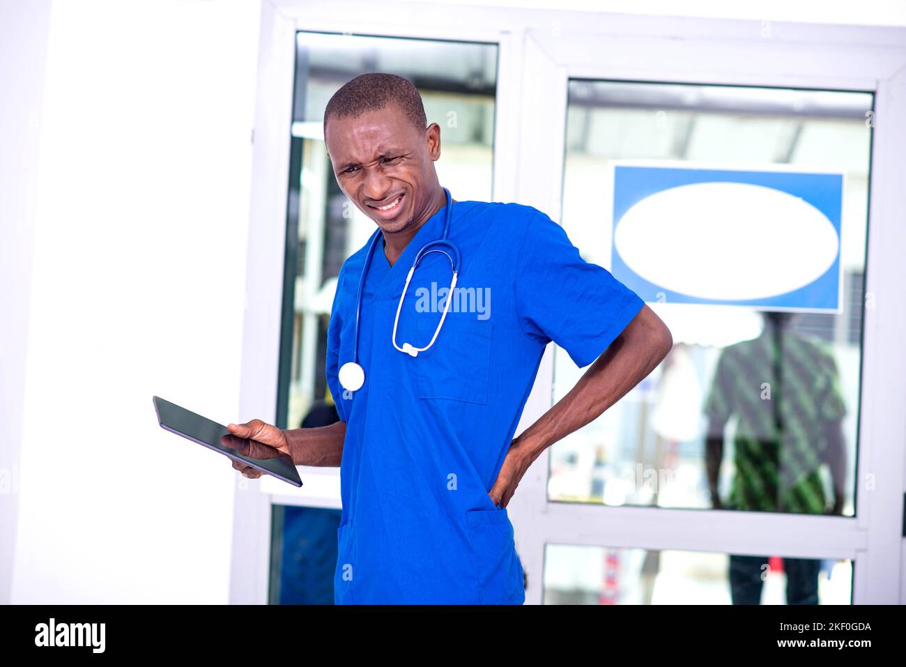 young male doctor with digital tablet suffering from back pain while ...