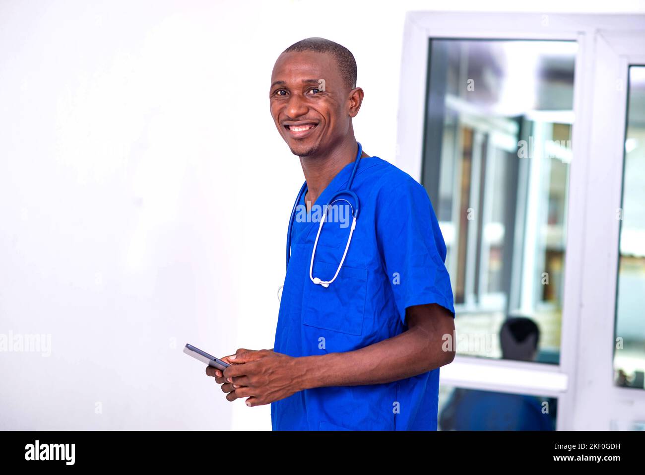 young male doctor wearing blue uniform holding digital tablet in ...