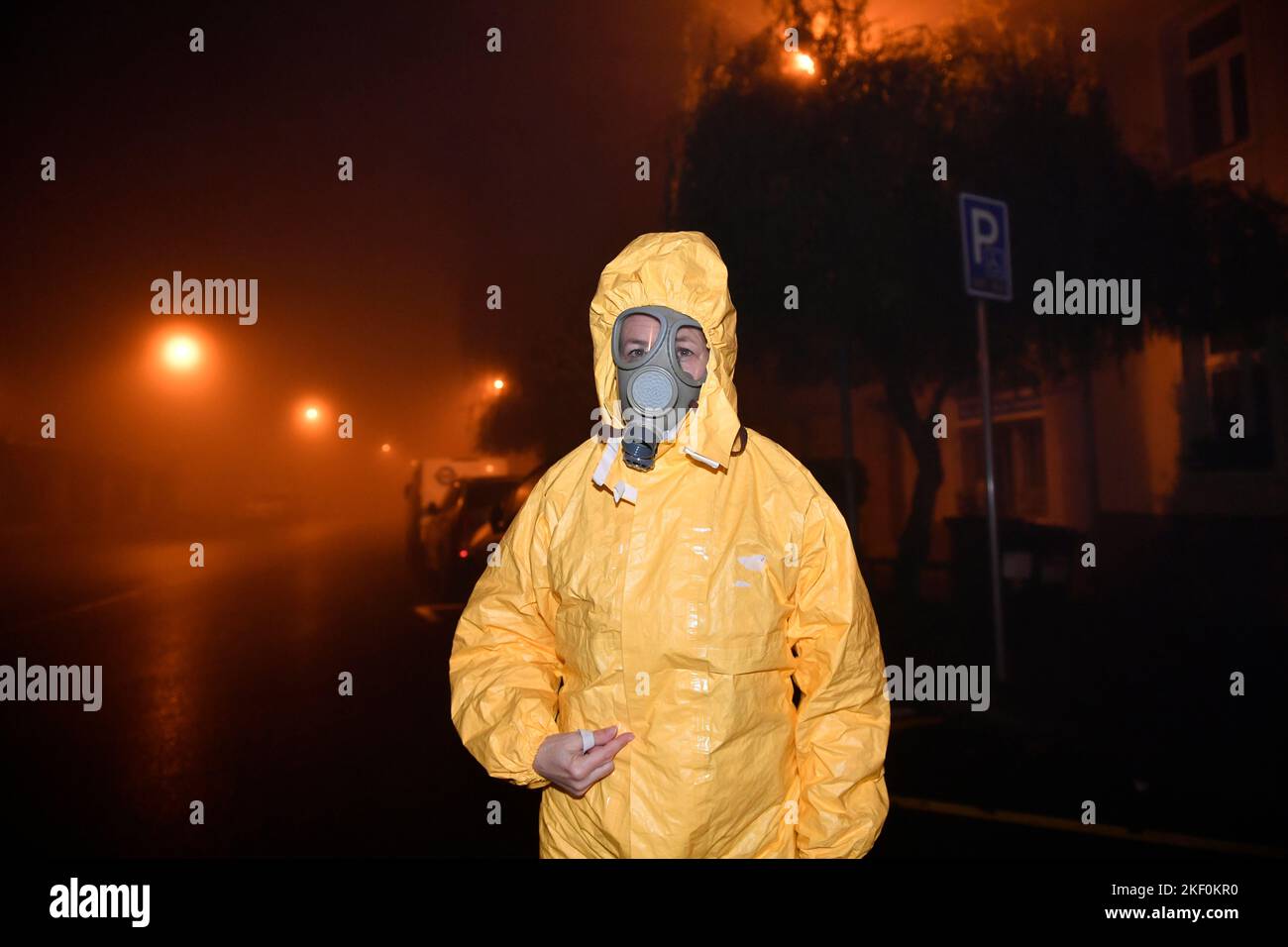 a person in yellow overall walking on the night smoggy road holding ...