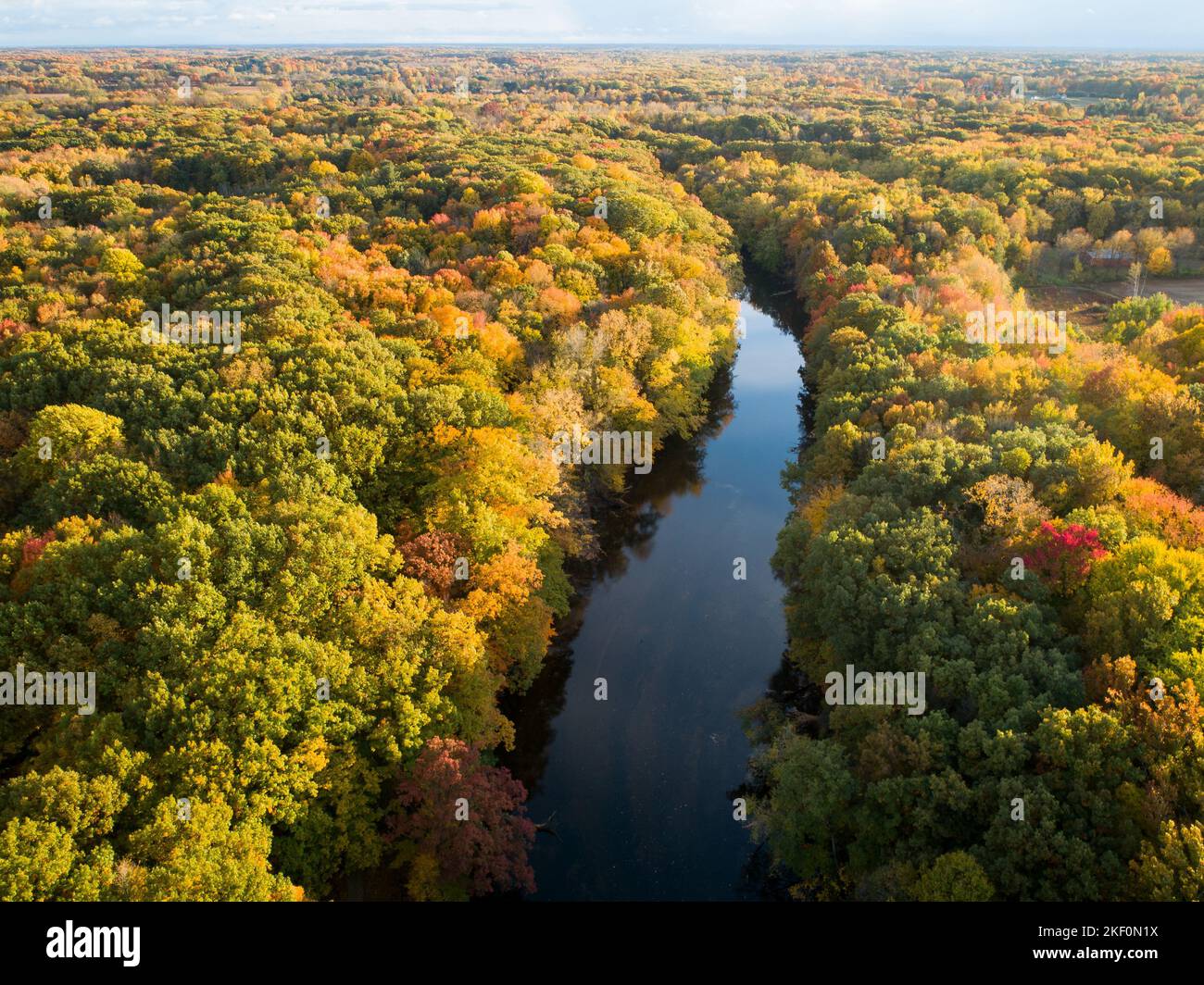 An aerial view of Michigan falls surrounded by forest in a warm autumn ...