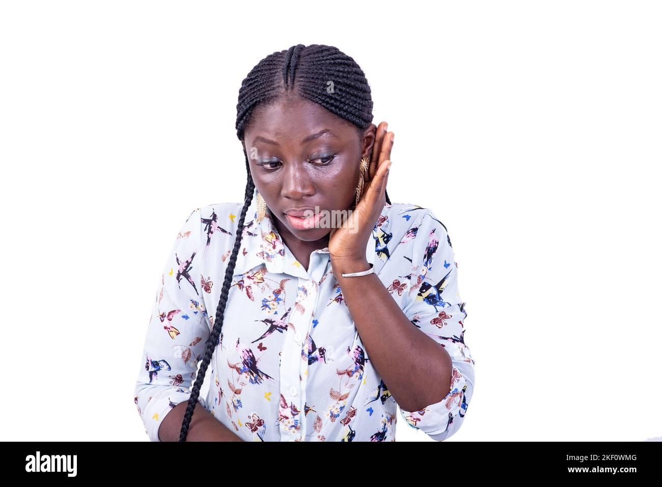 portrait of a beautiful young woman with hand to ear listening ...
