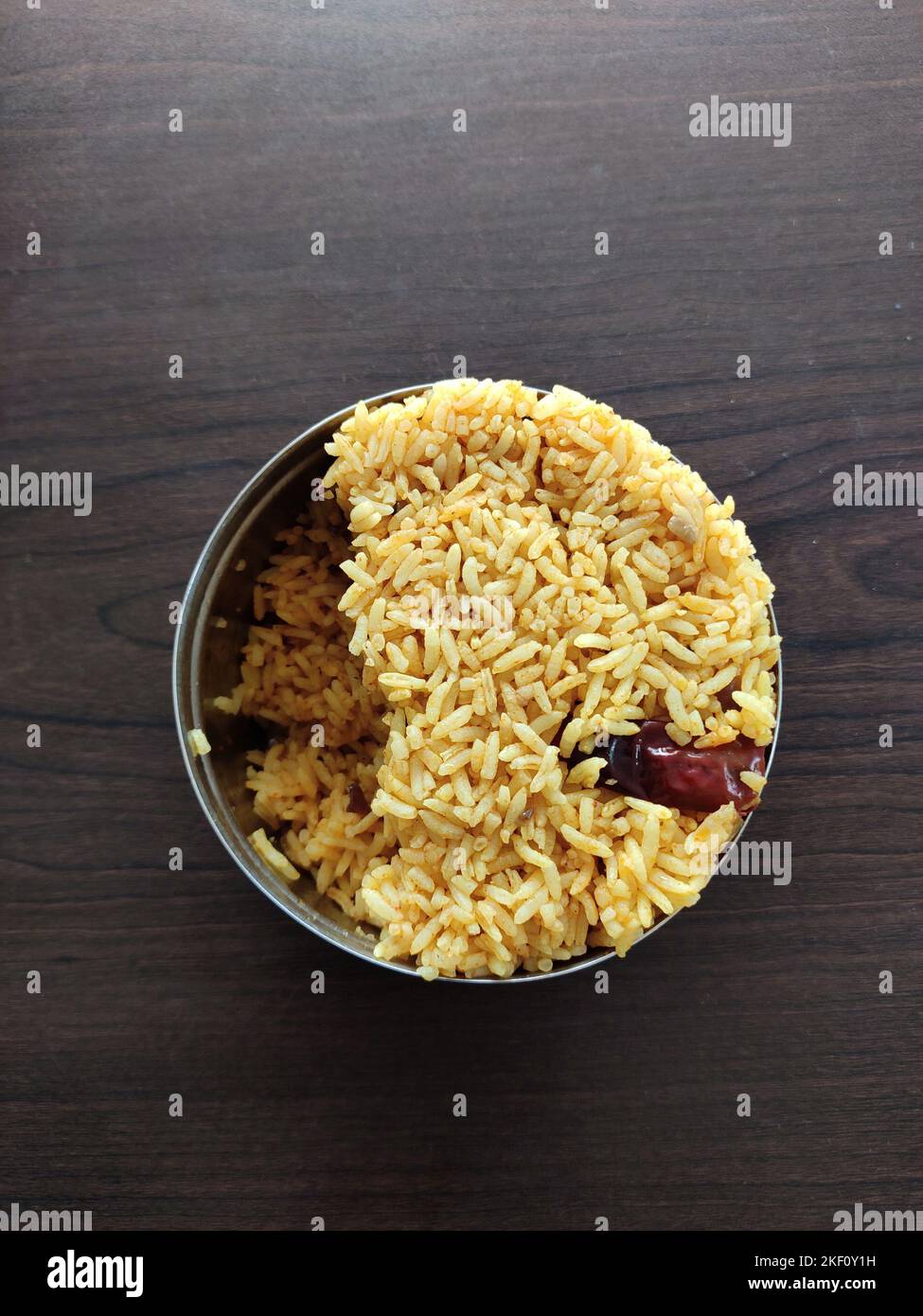 Closeup of onion rice in a stainless steel tiffin, vibrant yellow with ...