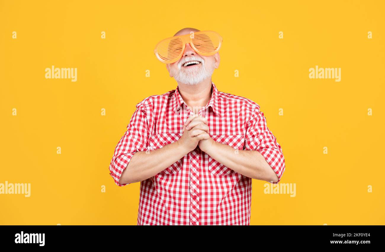 praying senior man with party glasses on yellow background Stock Photo ...