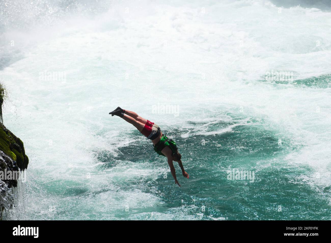young man jump into the water of the clean river on the waterfall ...