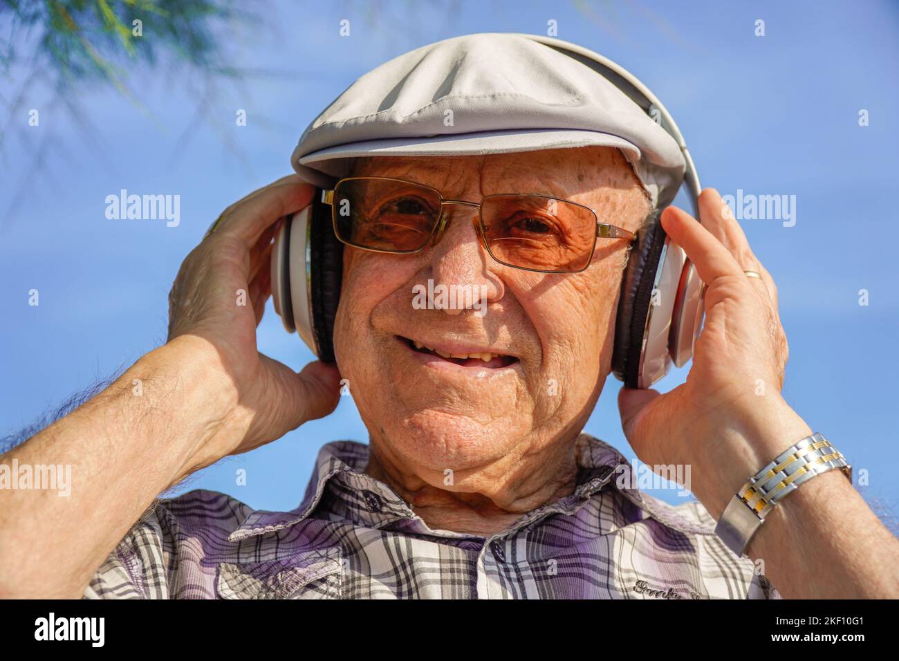 old man talking with a family with a headphone in a park. Elderly and ...
