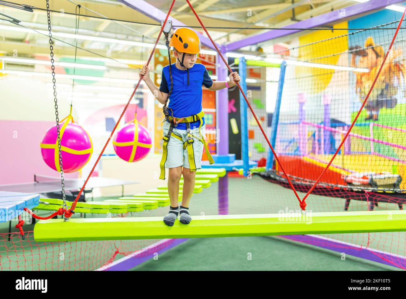 Boy in protective gear holding safety rope and passing obstacle course ...