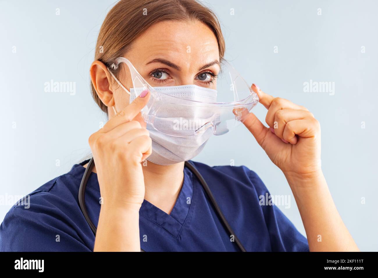 Female doctor putting on surgical face mask and medical goggle Stock ...