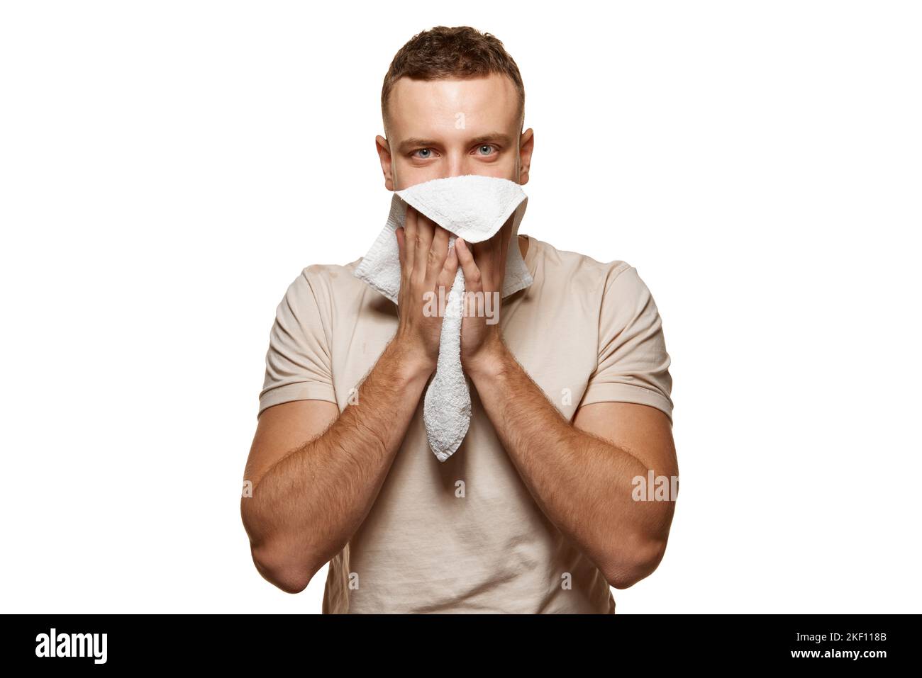 Portrait of young man wiping face after shaving isolated over white ...
