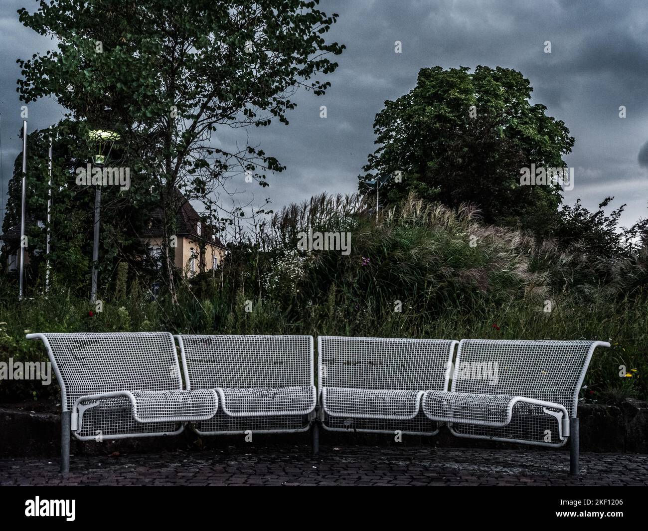 A metallic bench in the green park with dark clouds in the sky Stock ...