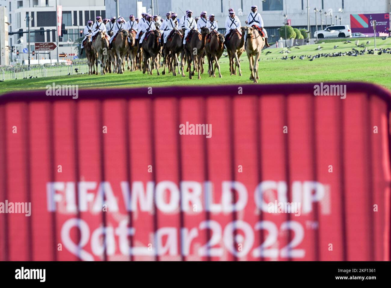 Doha, Qatar. 15th Nov, 2022. A group on camels rides past the lettering ...