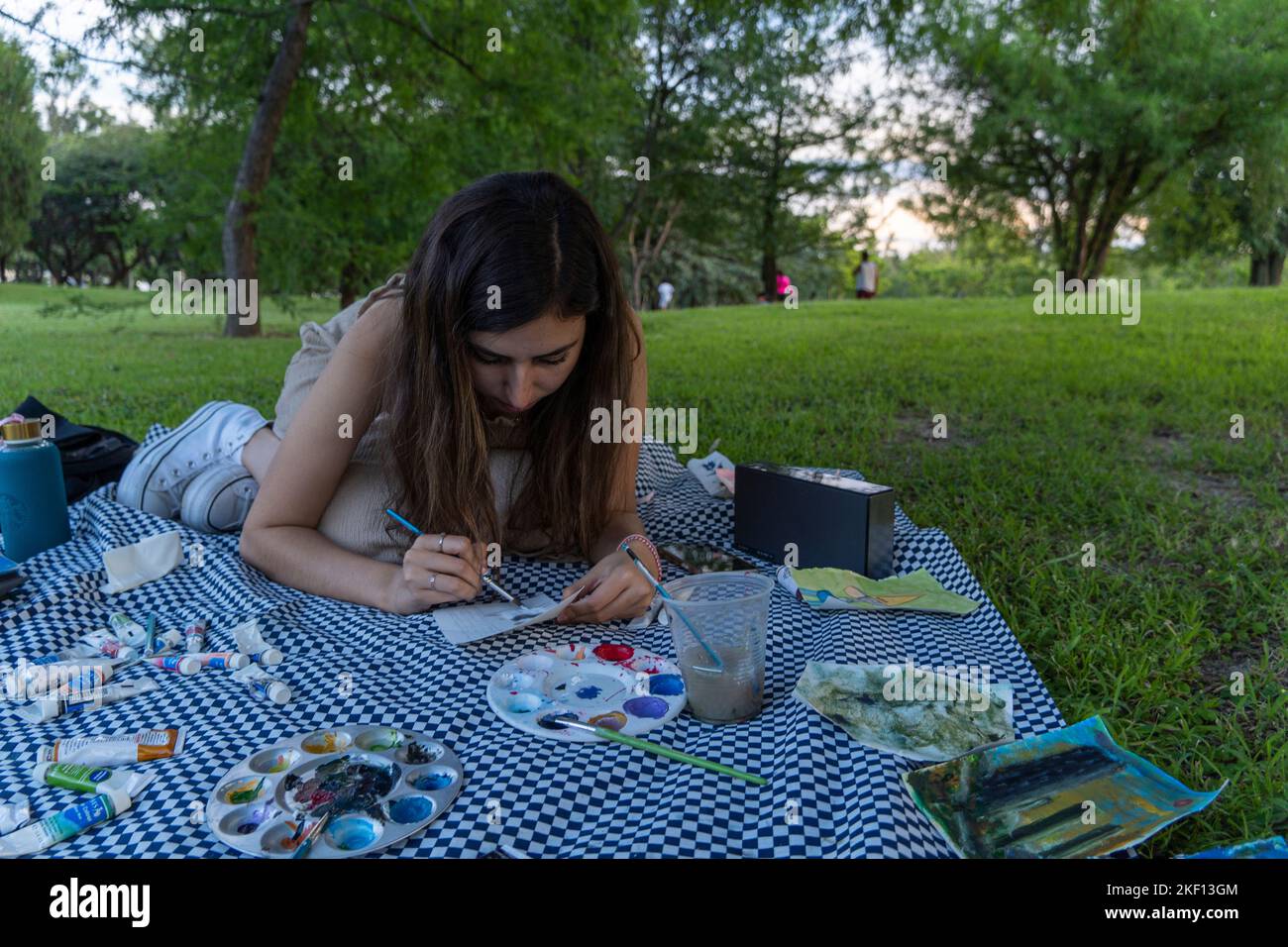 Young beautiful woman drawing a painting outdoors, talented artist with ...