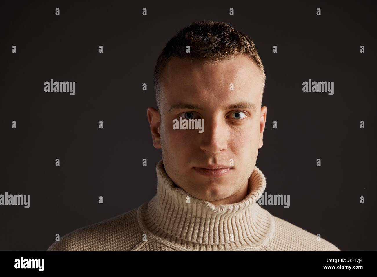 Portrait of handsome man posing in stylish sweater isolated over dark ...