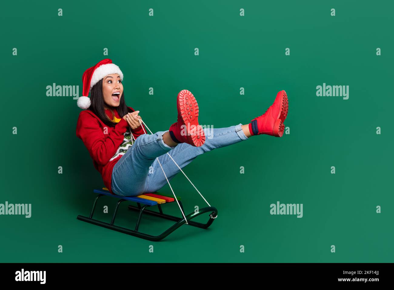 Full length photo of sweet funky girl dressed ugly print red x-mas pullover riding sledge ...