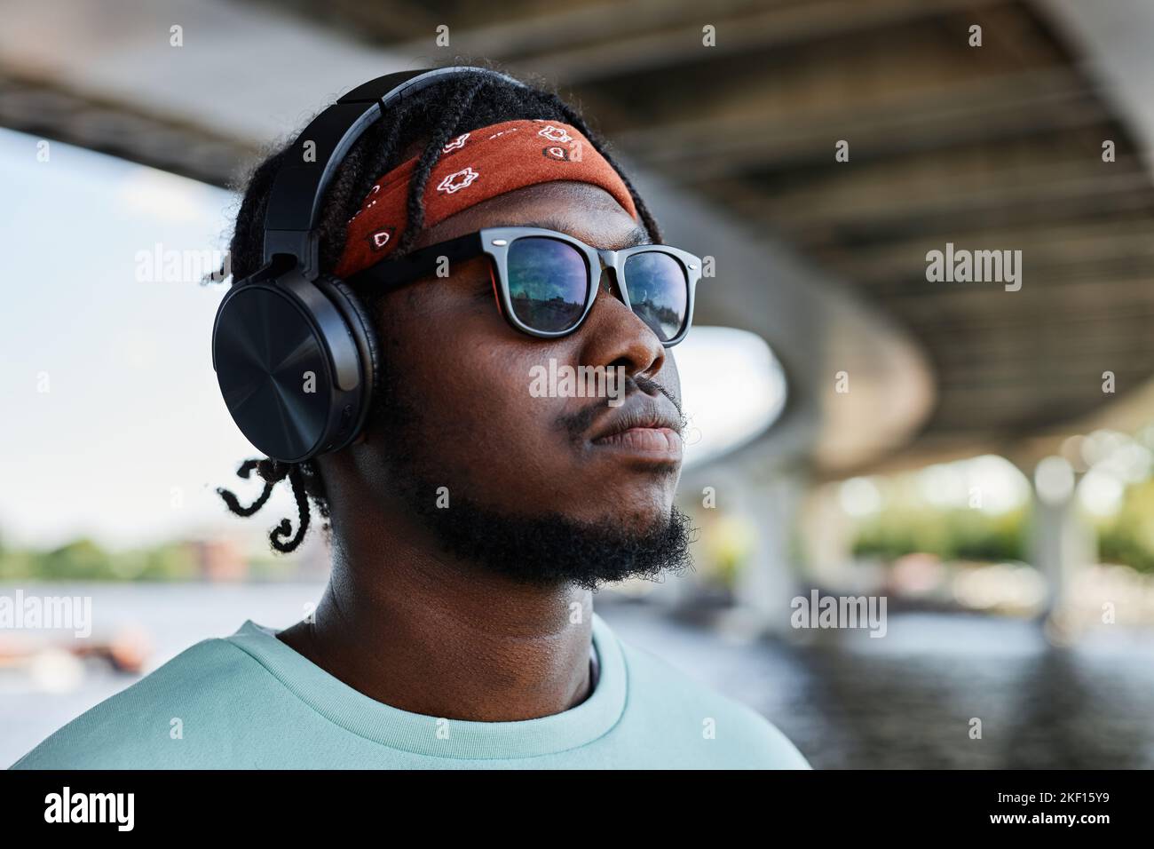 Closeup side view of young black man wearing headphones in urban city ...