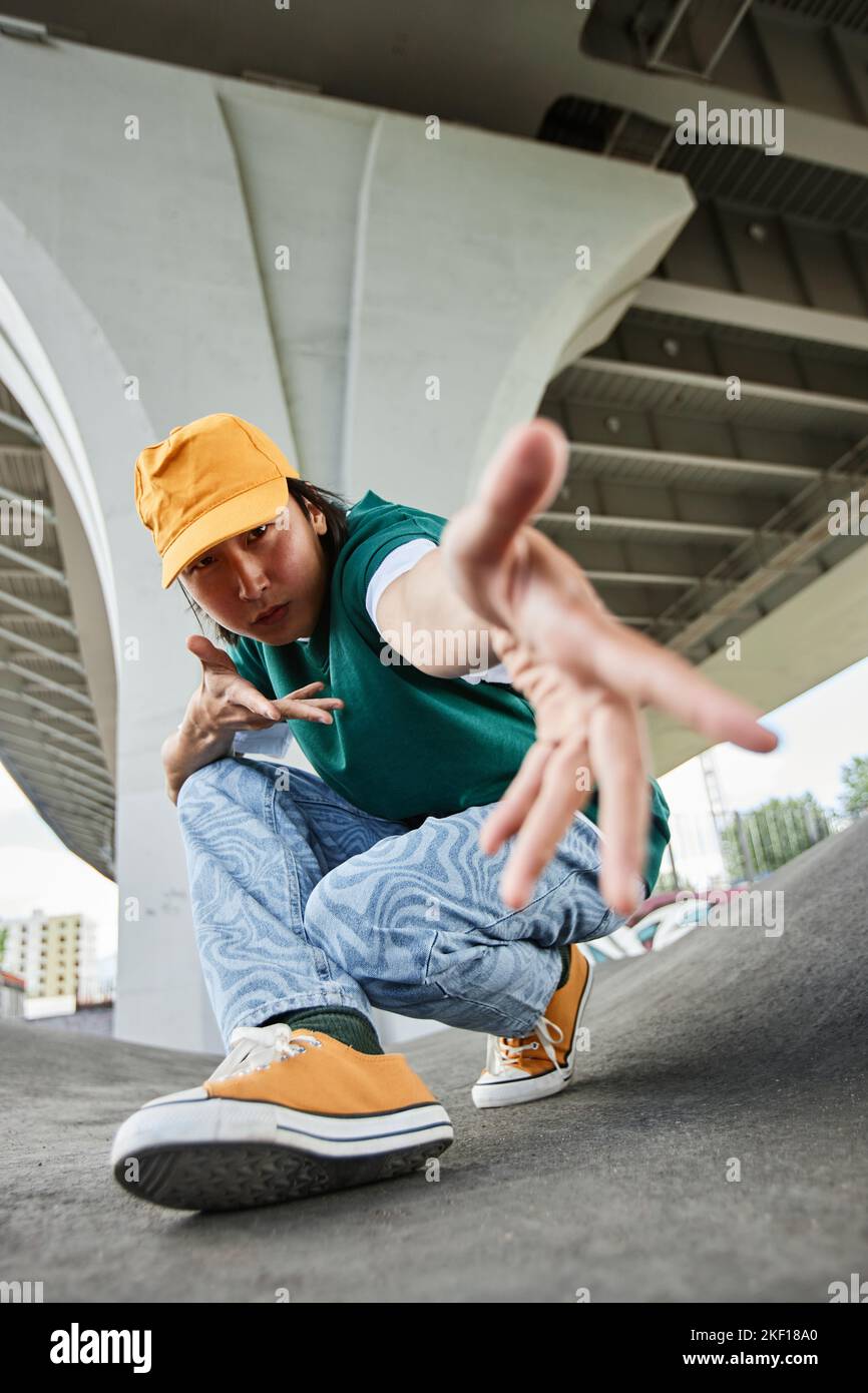 Fisheye of young Asian man dancing outdoors and gesturing to camera ...