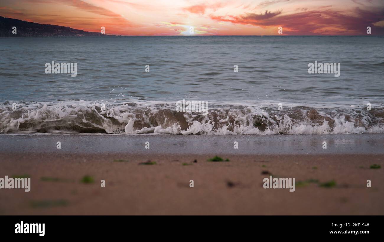 Colorful sunset at the tropical beach, sun behind clouds reflects on ...