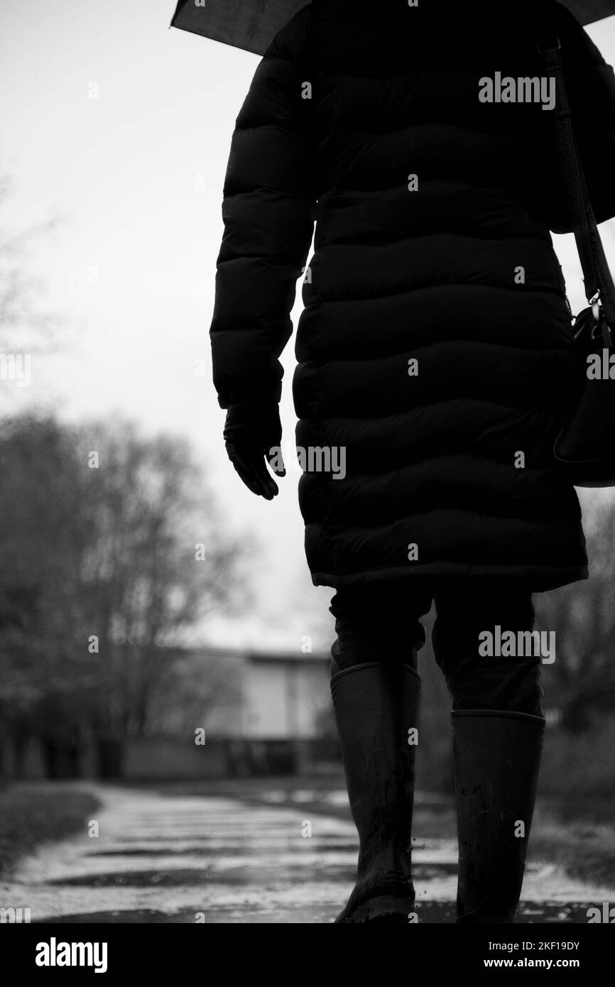 Rear view of isolated woman in silhouette with a brolly walking on a ...