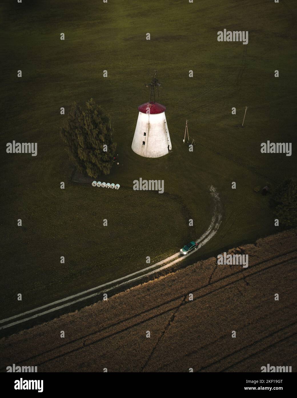 A drone view of a windmill with a tree in a green field Stock Photo - Alamy