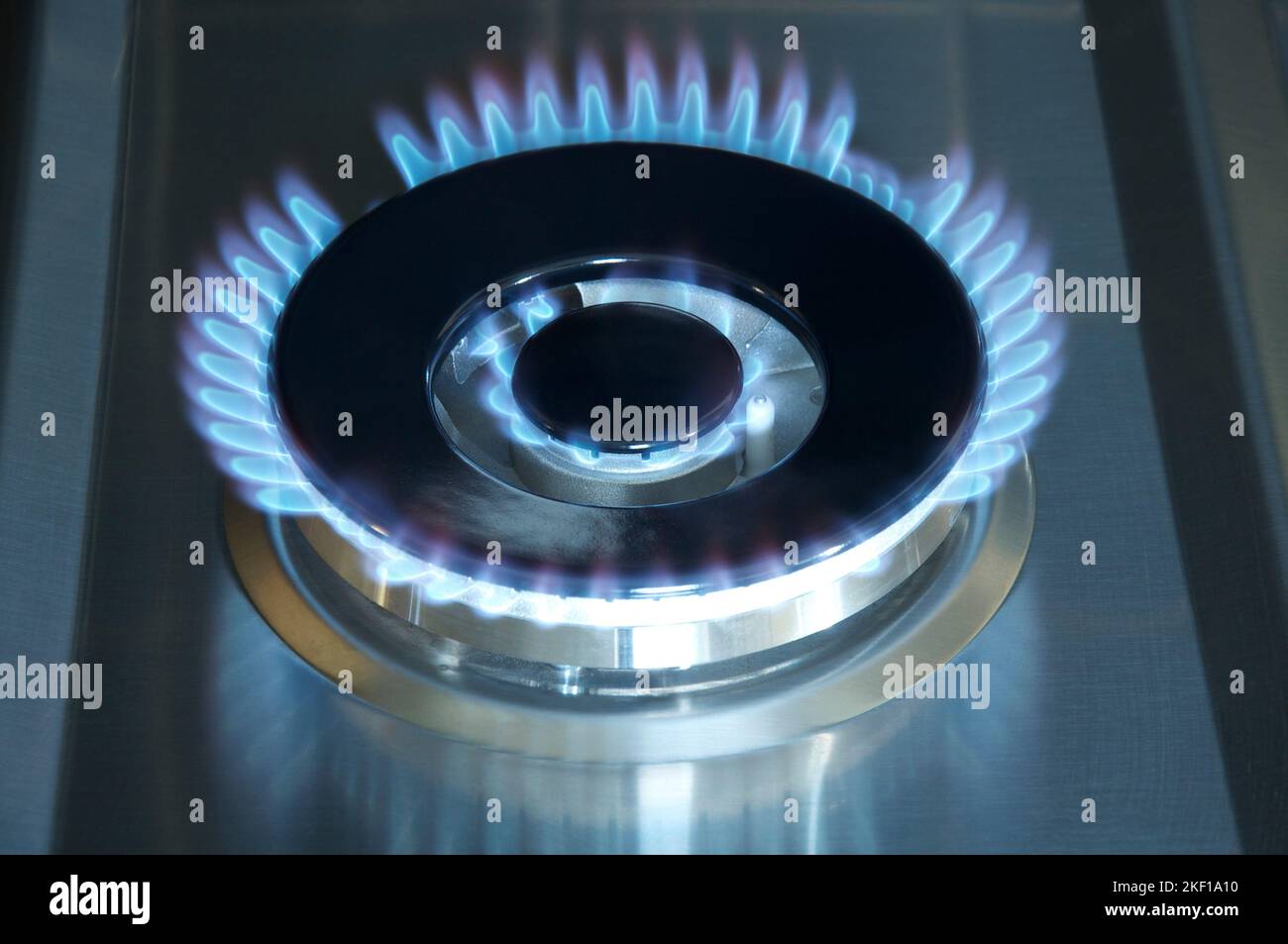 Blue flames burn from a lit gas jet on the hob of a kitchen cooker ...