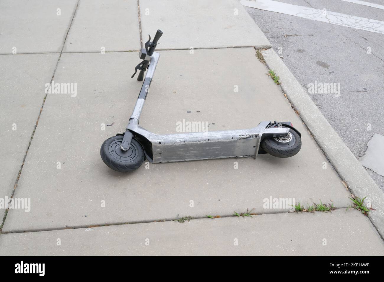 scraped up silver electric scooter lying down on sidewalk Stock Photo ...
