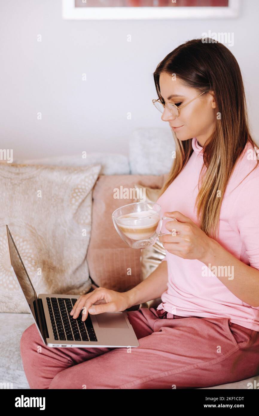 a girl in the morning in pajamas at home working on a laptop with ...