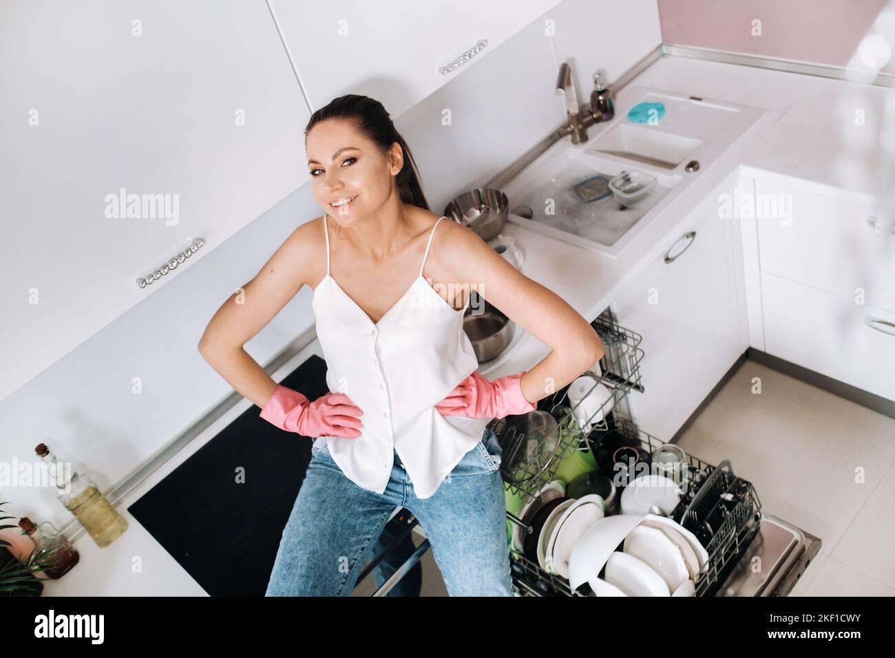 a housewife girl in pink gloves after cleaning the house sits tired in ...