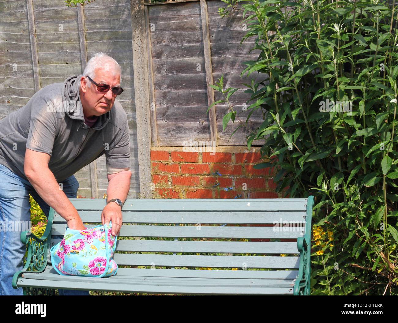 Thief leaning over a park bench and stealing property from a handbag ...