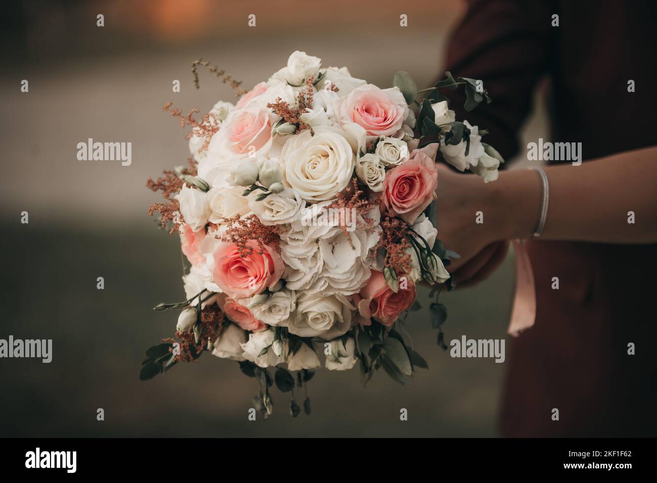 A closeup shot of a bride and groom holding a bouquet of flowers after ...