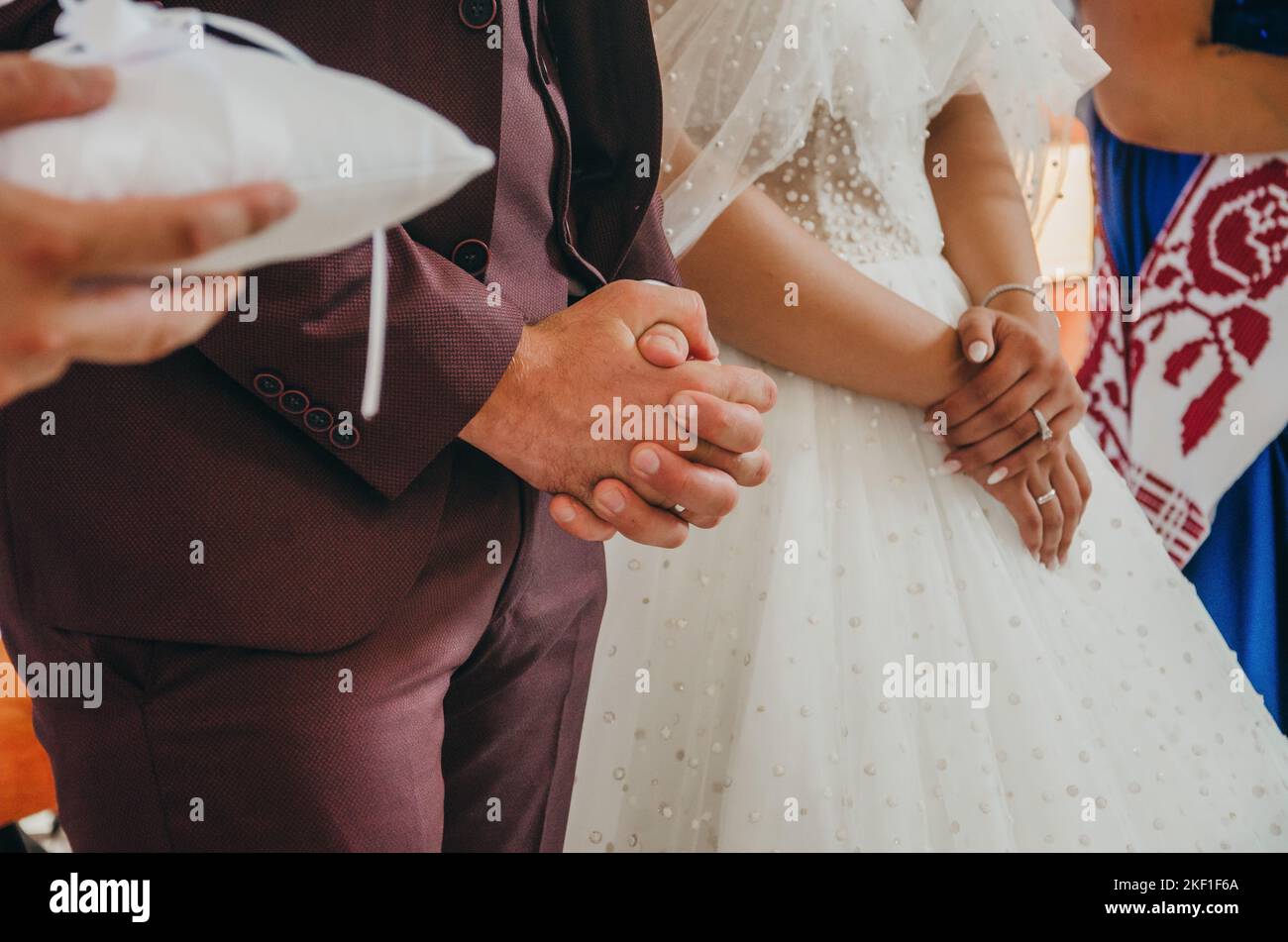 A closeup shot of the bride and the groom holding their own hands ...