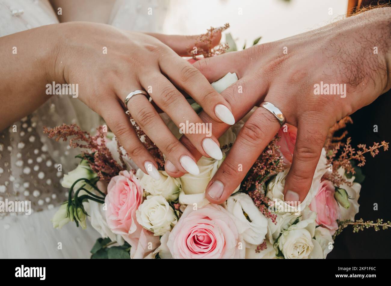 A closeup shot of the bride and groom wearing their new wedding rings ...