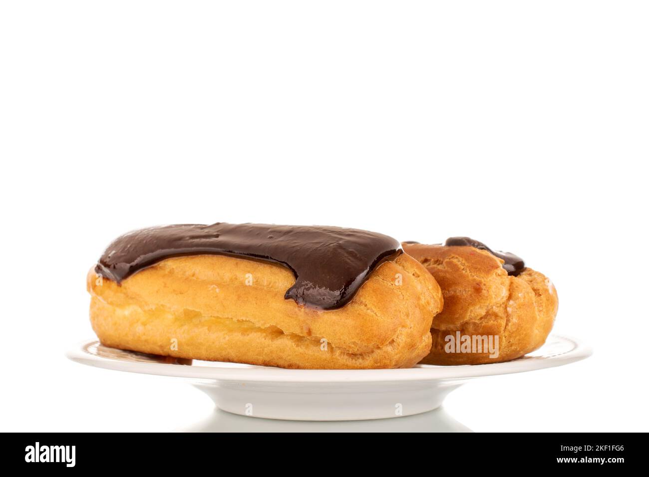 Two sweet chocolate eclairs on a white ceramic plate, macro, isolated ...