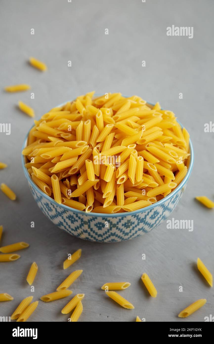 Homemade Raw Dry Mini Penne Pasta in a Bowl on a gray background, side ...