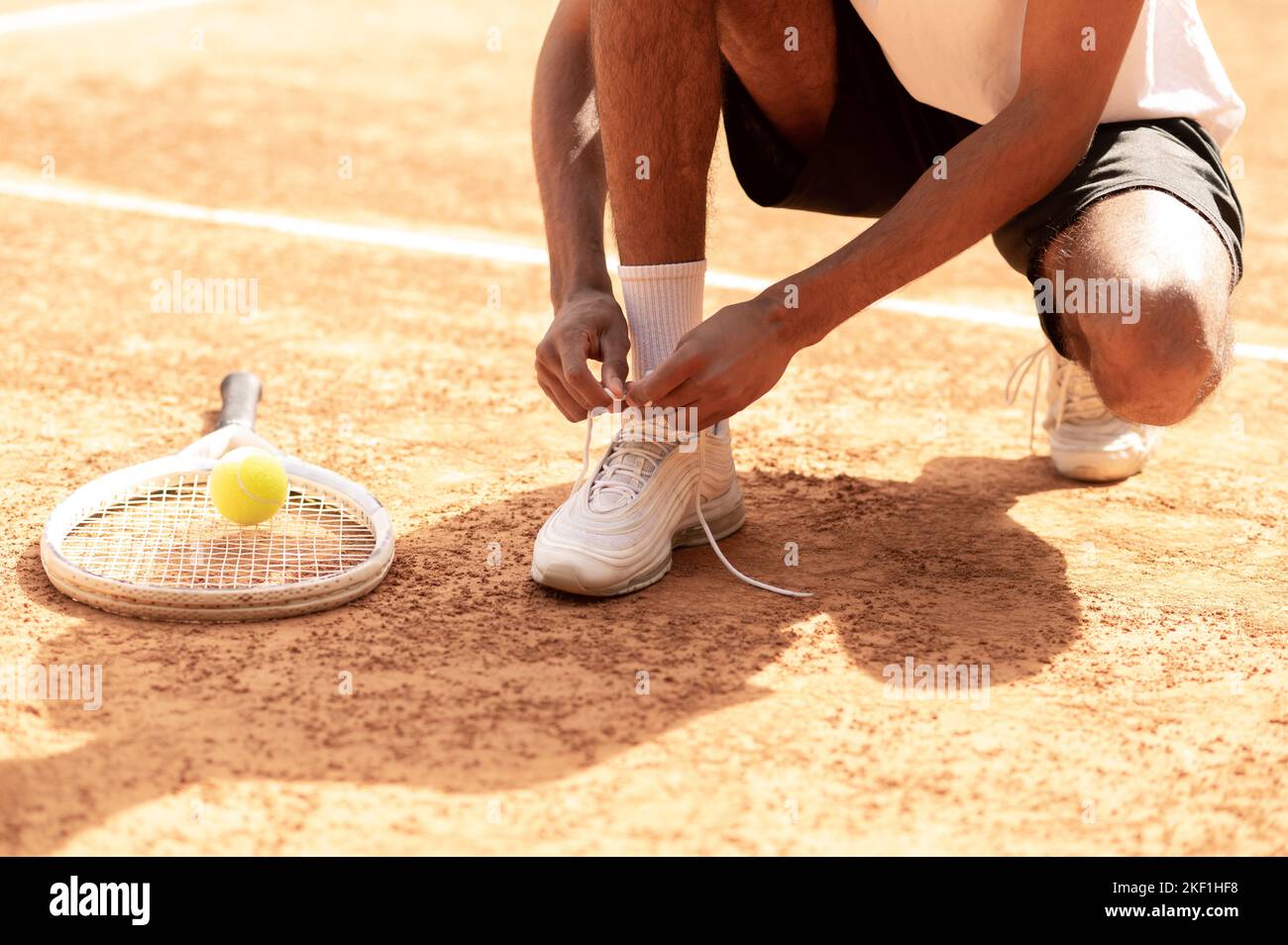Man in sports shorts tying shoe-strings on his sneakers Stock Photo - Alamy