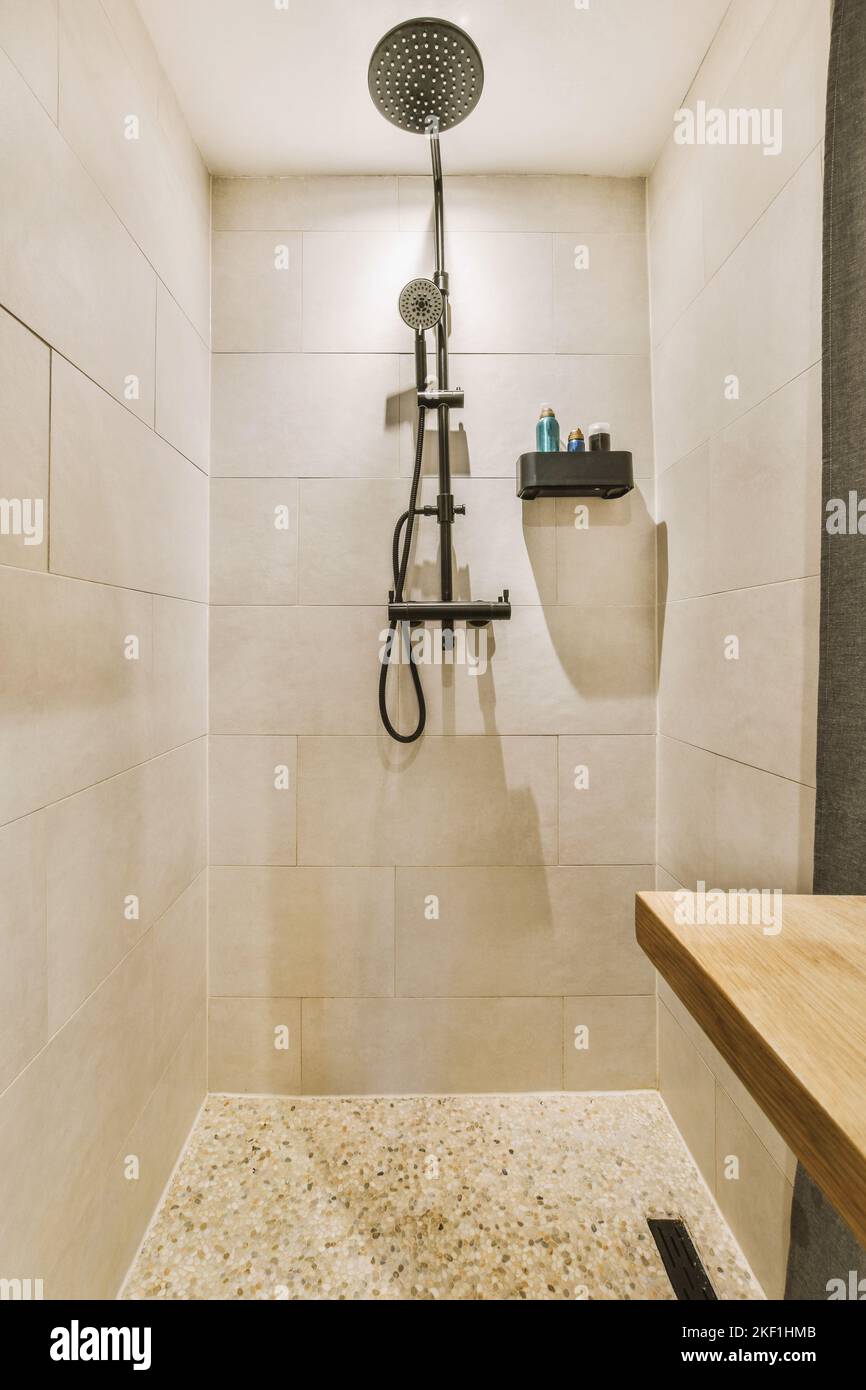 Shower faucets attached to tiled wall near glass partition and ...