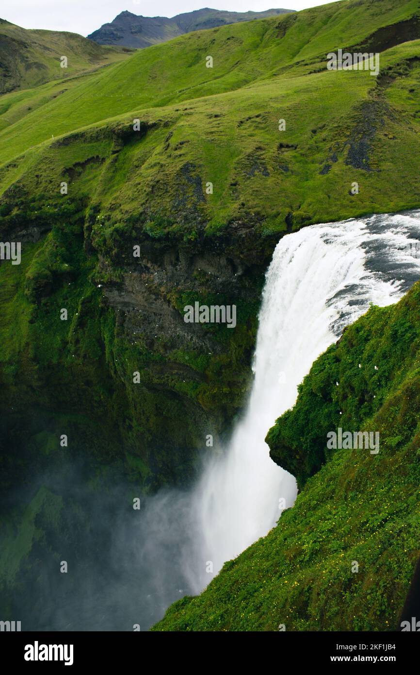 A high-angle vertical closeup of Skogafoss waterfall valleys covered ...