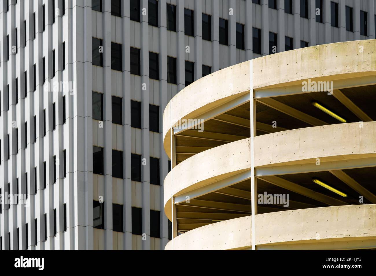 Round, metal clad parking garage in faded yellow backed by monochrome ...