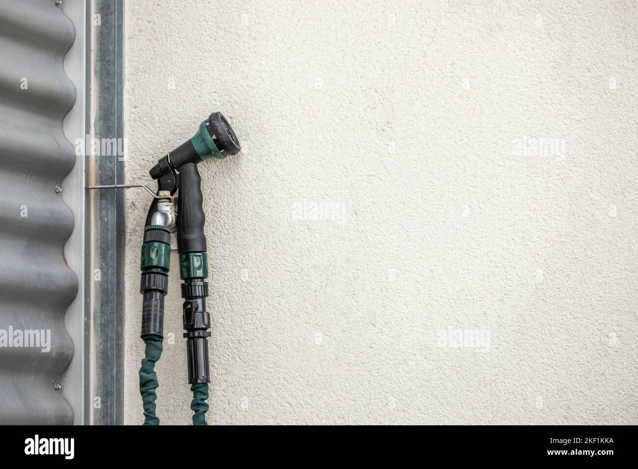 Water tap from a rubber green colored hose attached to the wall on a ...