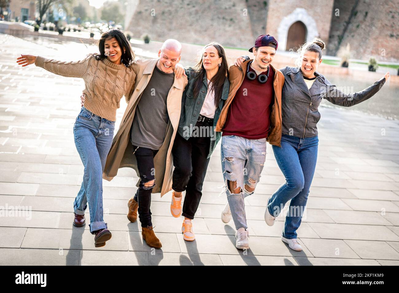 International trendy friends walking at city center playing funny crazy ...