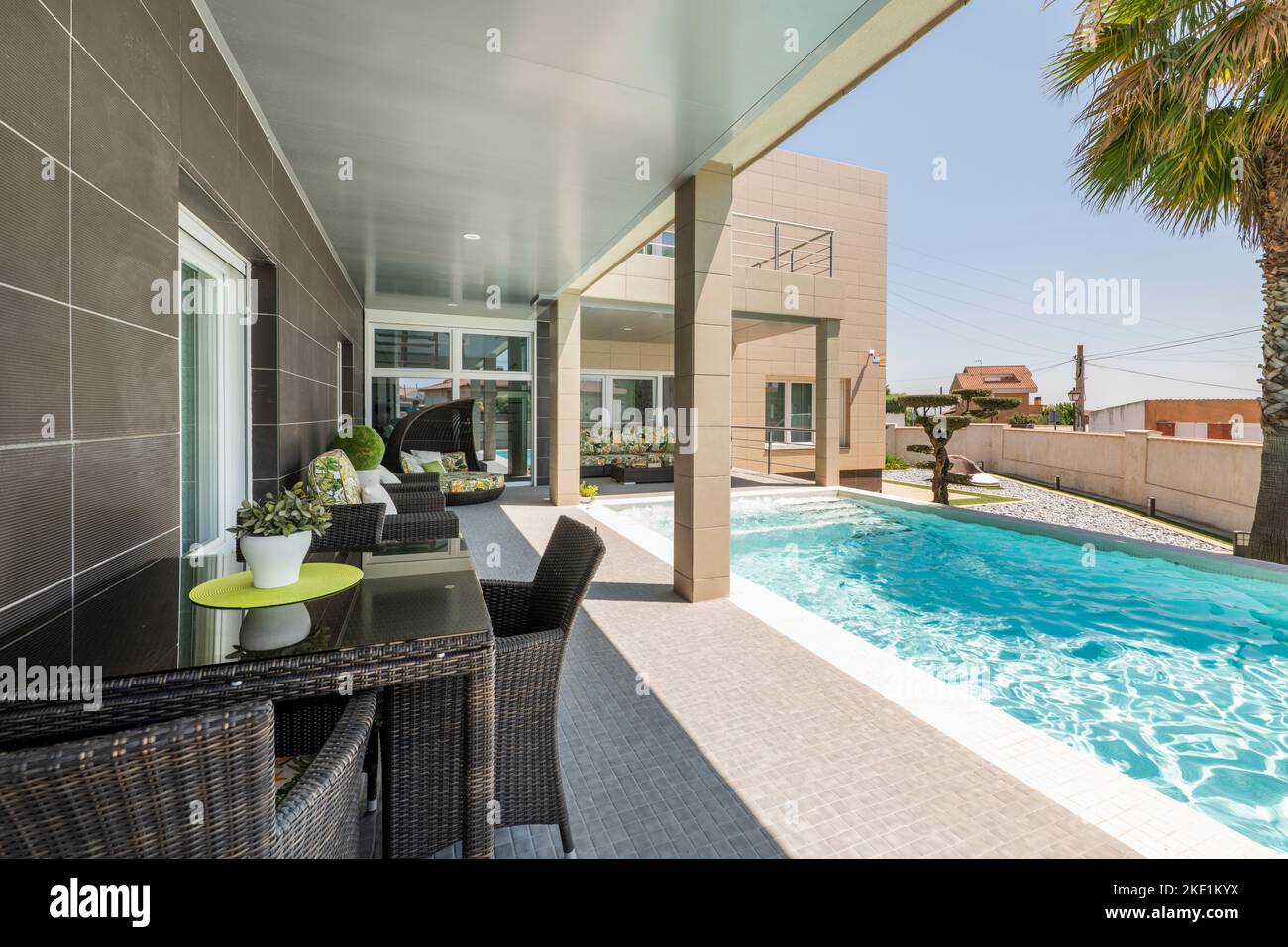 Swimming pool of a single-family house with a porch with dark wicker ...