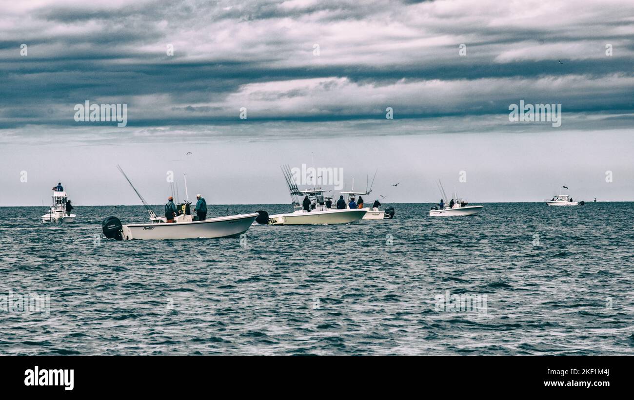 A group of people on small boats voyaging and fishing in the blue sea ...